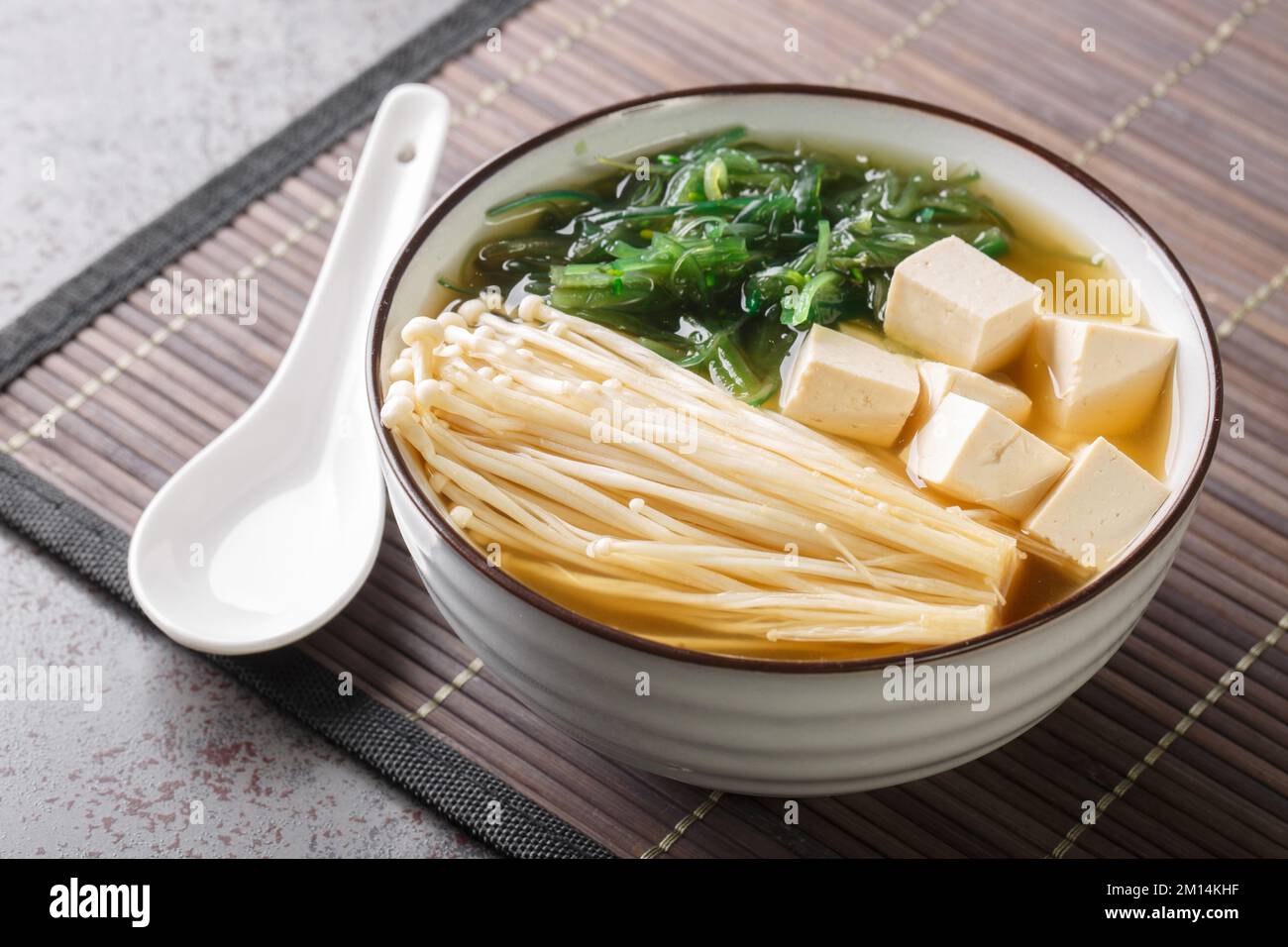 Rich miso soup with enoki mushrooms, wakame seaweed and tofu, vegetarian, vegan Asian food close ...