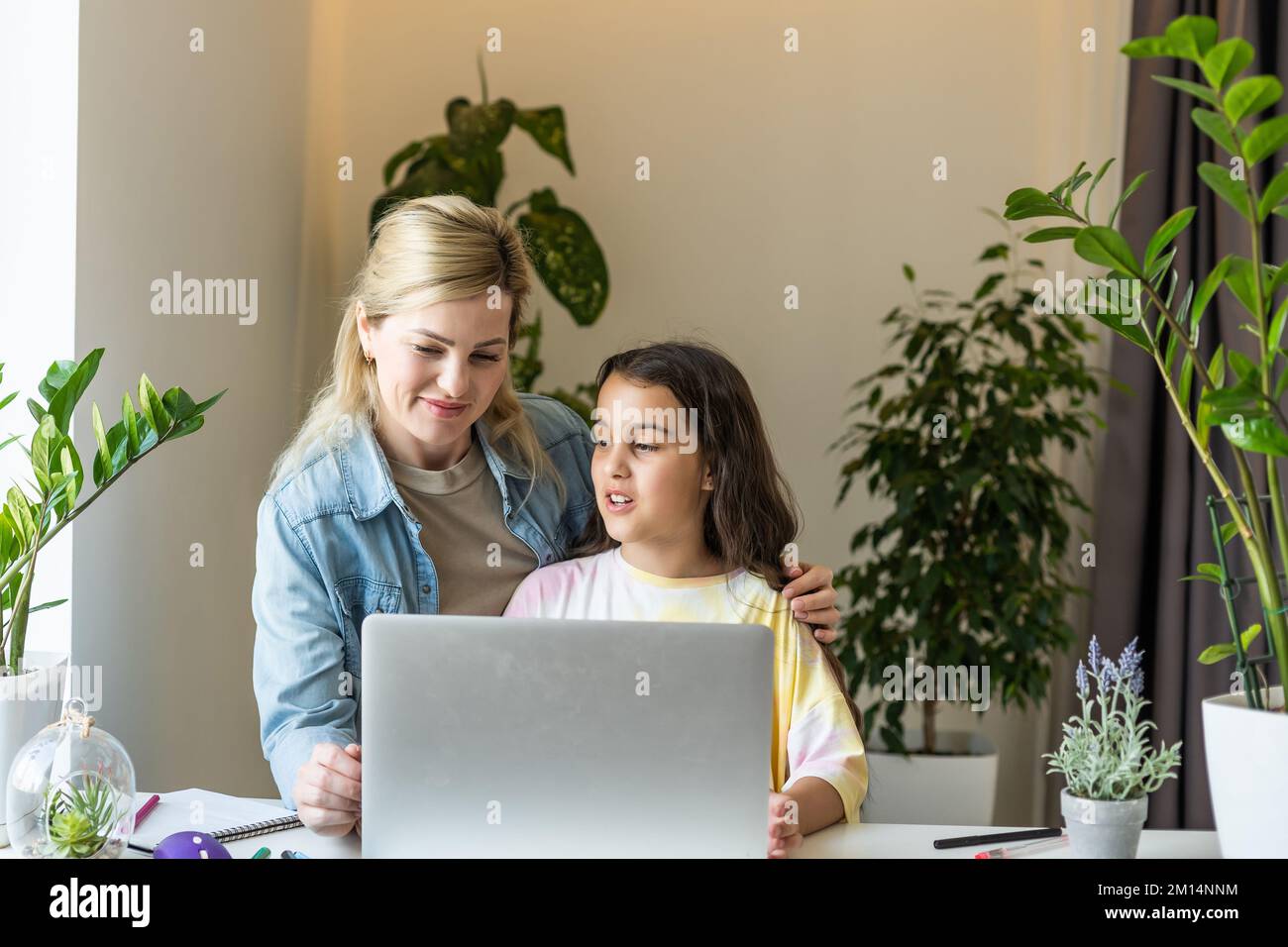 Beautiful mother and child looks at laptop screen spend time in kitchen ...