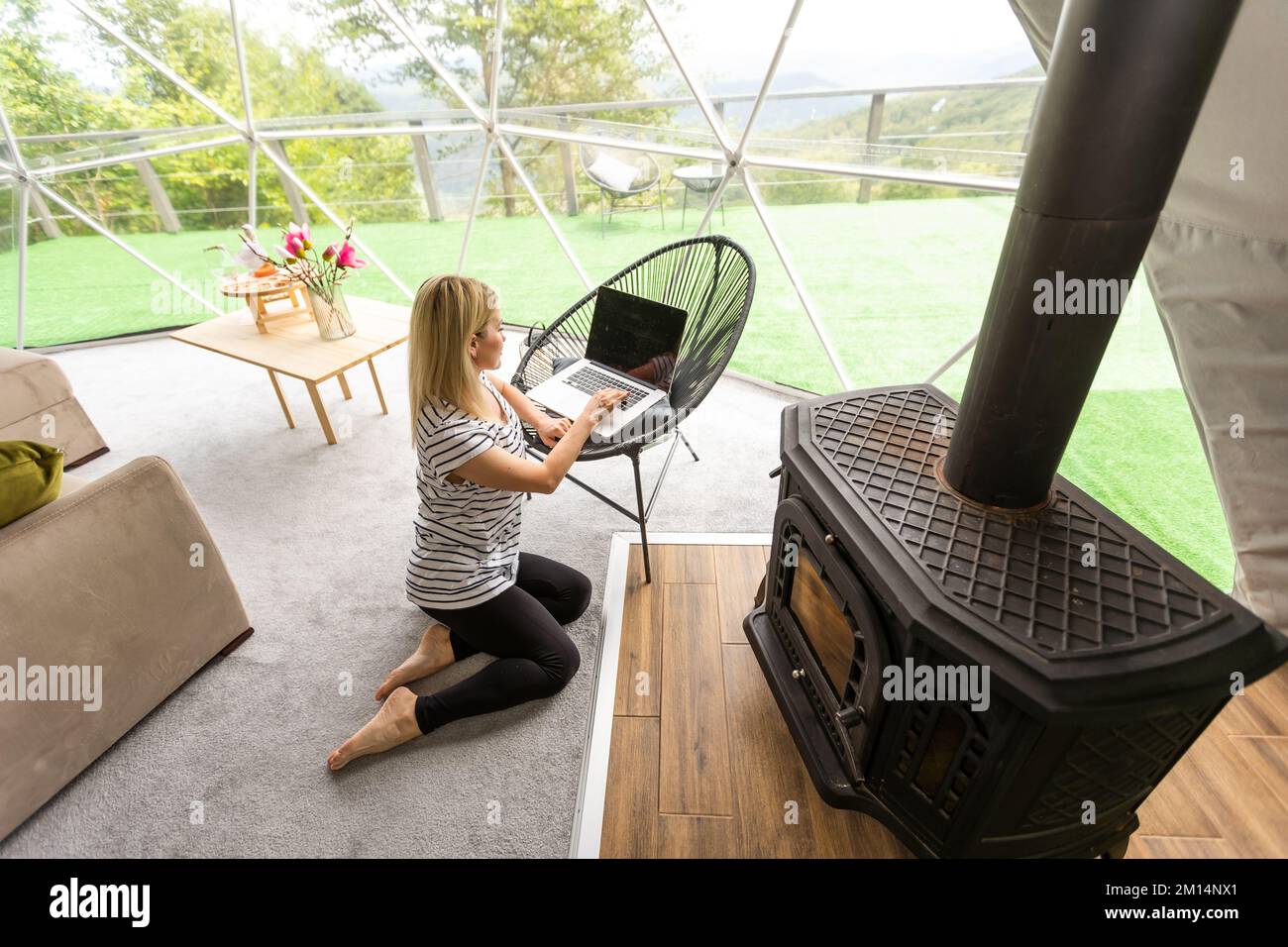 Woman working on laptop geo dome tents. Green, blue background. Cozy, camping, glamping, holiday ...