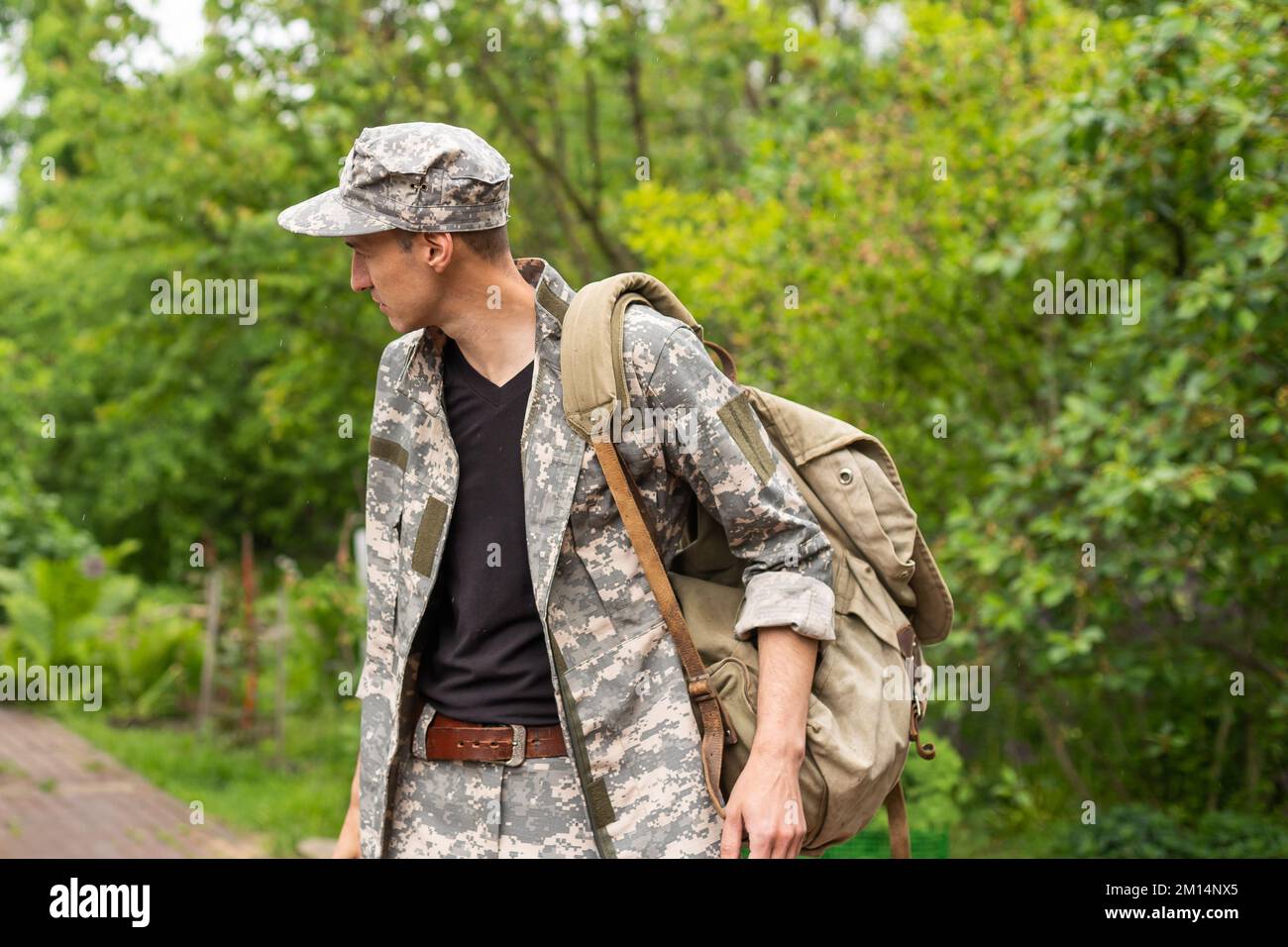 Photo of soldier in camouflaged uniform holding olive colored backpack ...