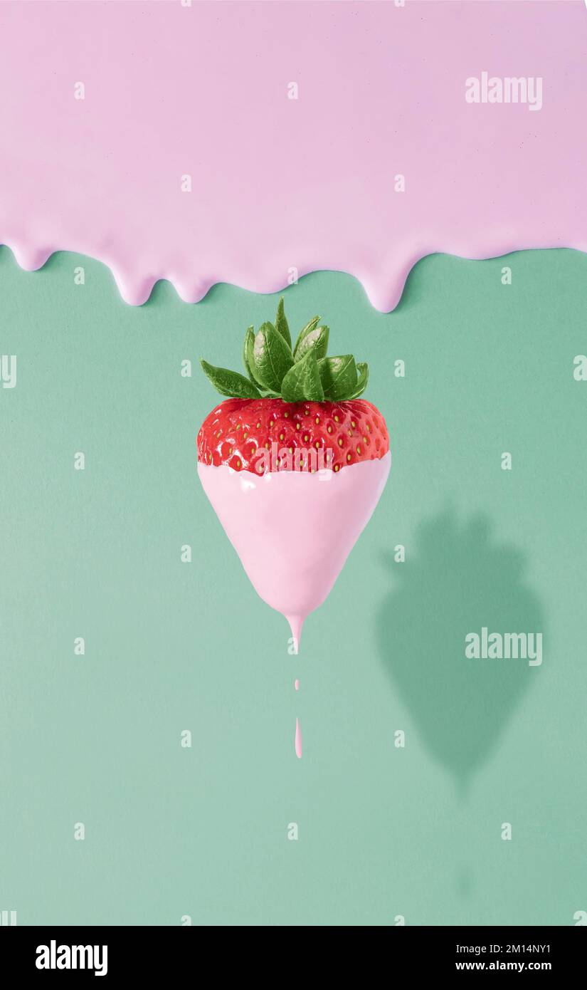 A vertical of a strawberry dripping with pink paint on a pink and green ...