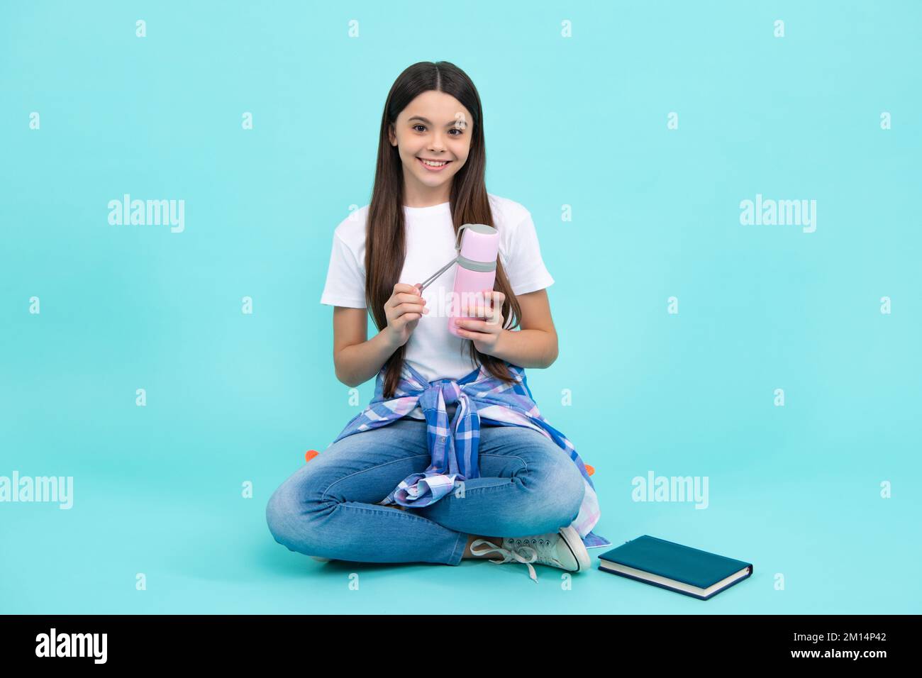 12, 13, 14 year old girl holds thermos and mug of hot tea. Happy ...