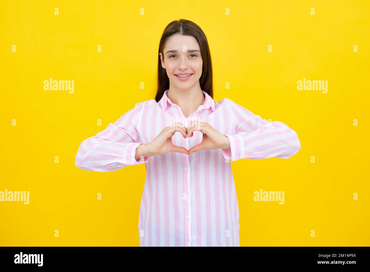 Pretty romantic young woman making a heart gesture, showing love and ...