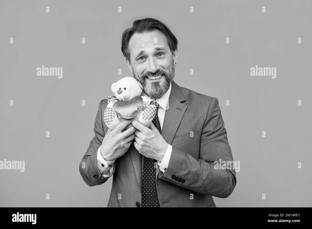 happy senior businessman in suit hold toy bear on grey background ...
