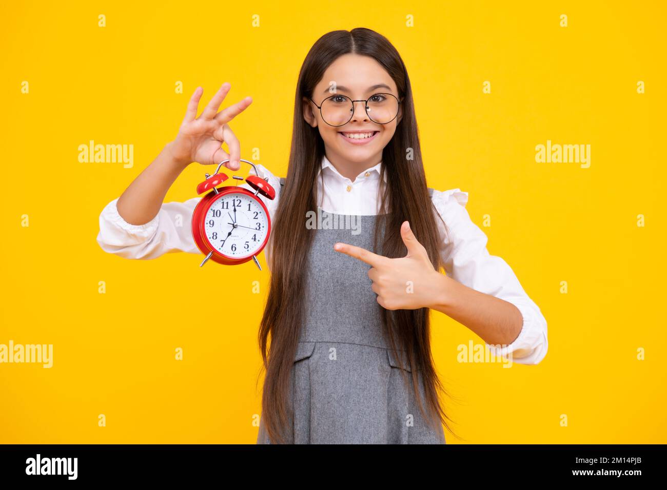 Child student girl with clock isolated on yellow background. Child back ...