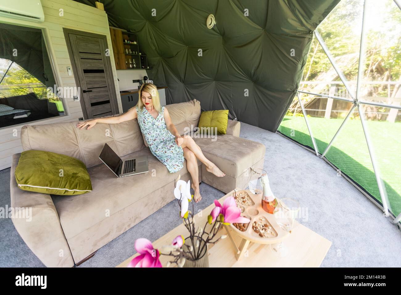 Woman working on laptop geo dome tents. Green, blue background. Cozy, camping, glamping, holiday ...