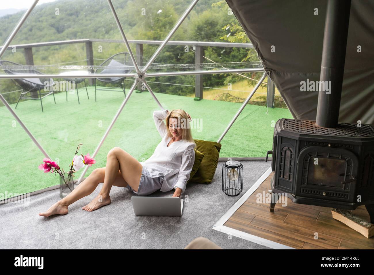 Woman working on laptop geo dome tents. Green, blue background. Cozy, camping, glamping, holiday ...