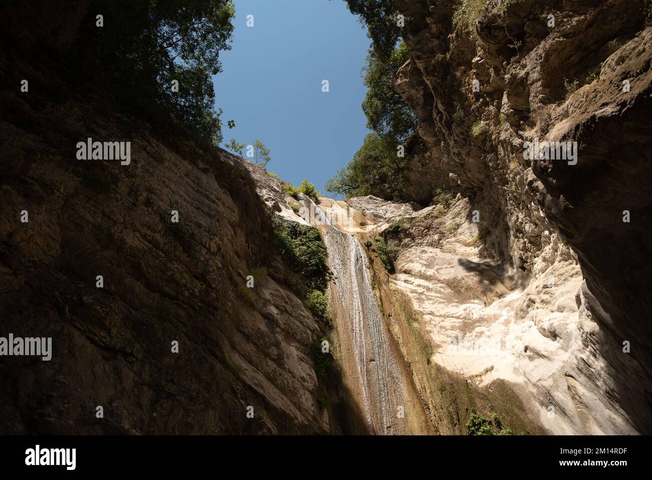 A low-angle of Dimosari waterfalls on Lefkada island sunlit clear sky ...