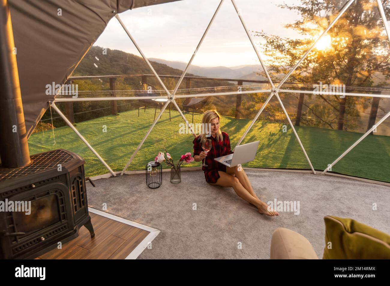 Woman working on laptop geo dome tents. Green, blue background. Cozy, camping, glamping, holiday ...