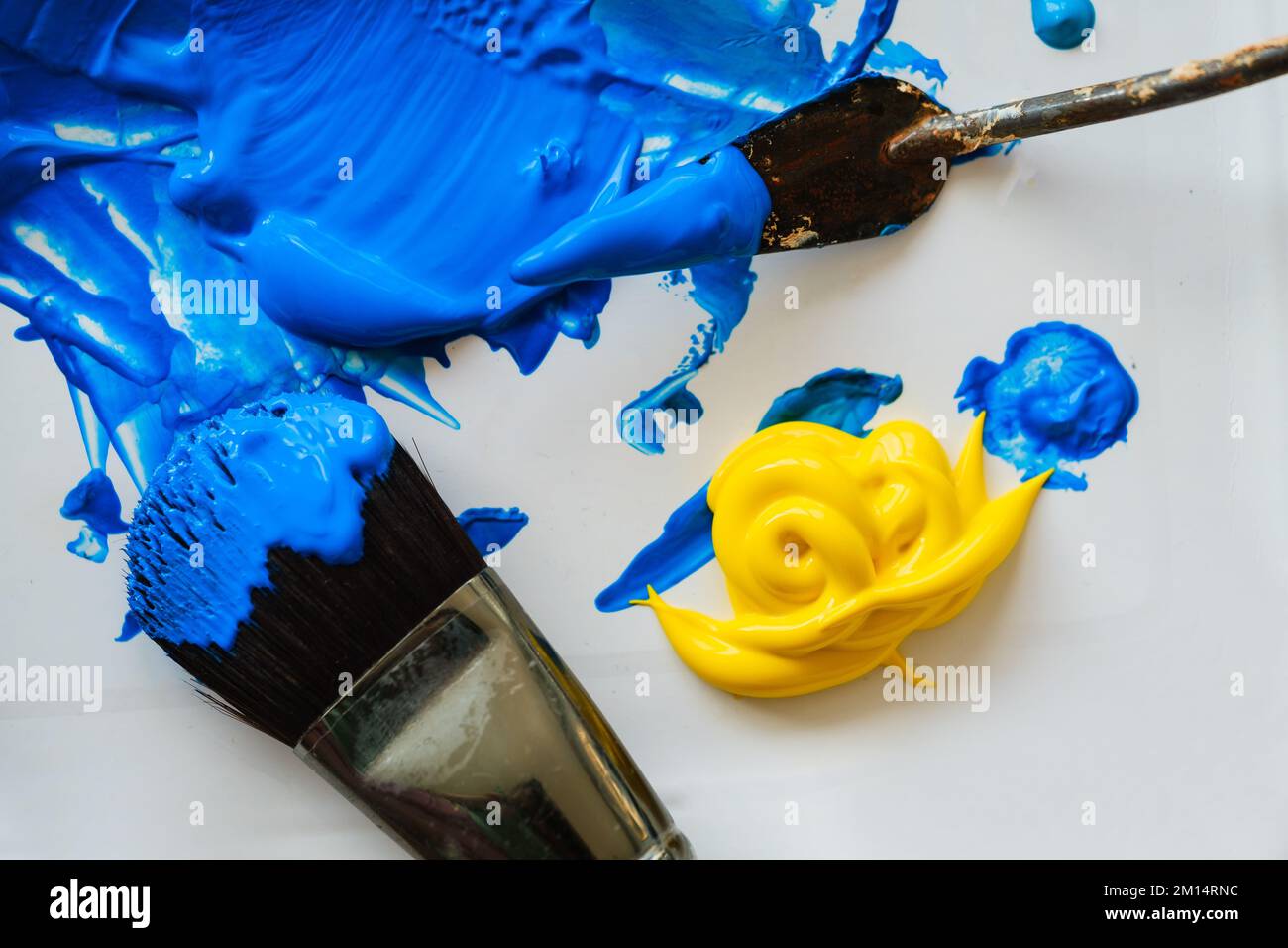 Overhead shot of brushes for painting, puddle of blue, and yellow paint ...