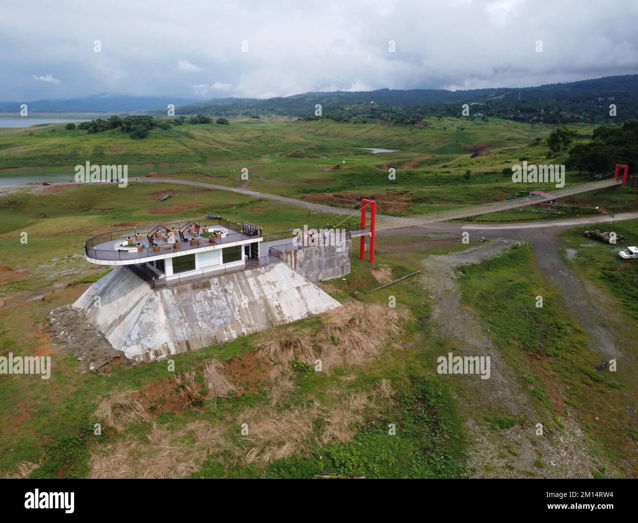 A high-angle of building in the field with mountains and cloudy sky ...