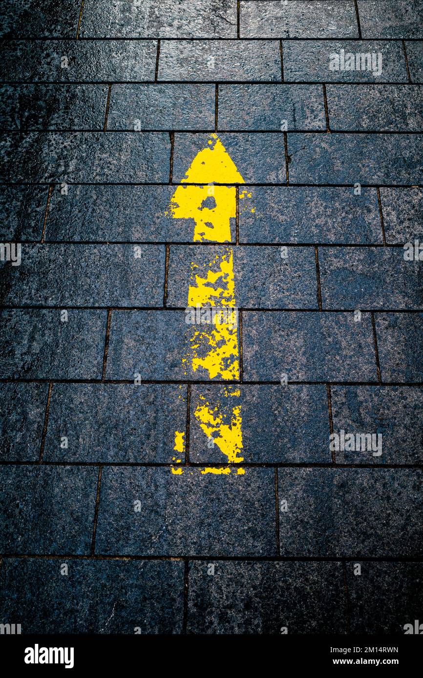 Yellow directional arrow painted on the floor Stock Photo - Alamy