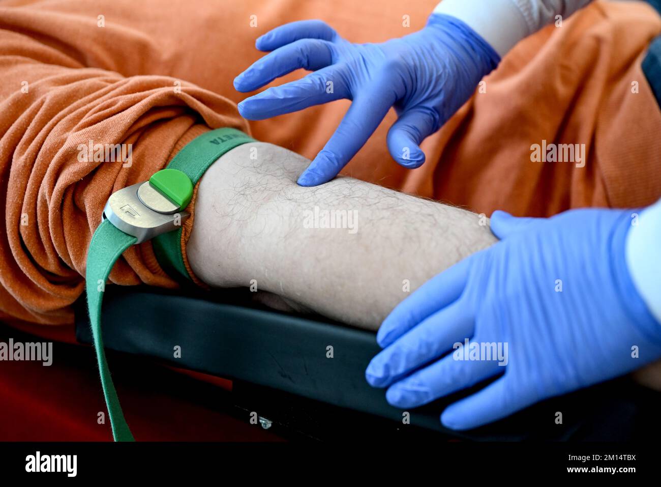 06 December 2022, Berlin: A nurse looks for a vein to draw blood at a ...