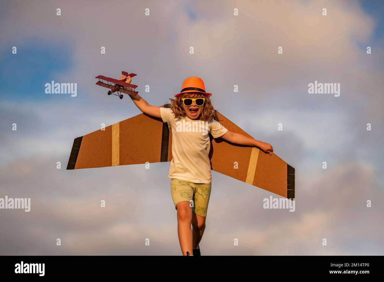 Little child boy is playing and dreaming of flying over the clouds ...