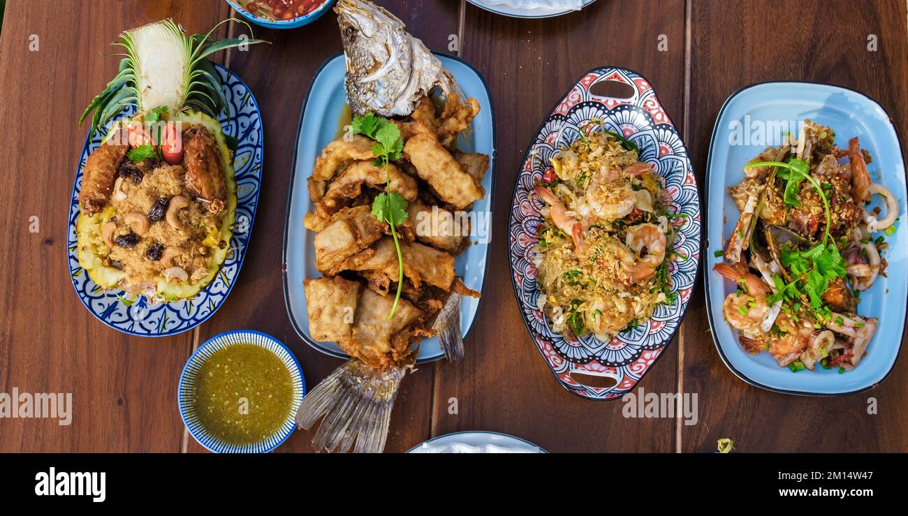 Dinner table with Thai food and bbq fish on the beach of Pattaya ...