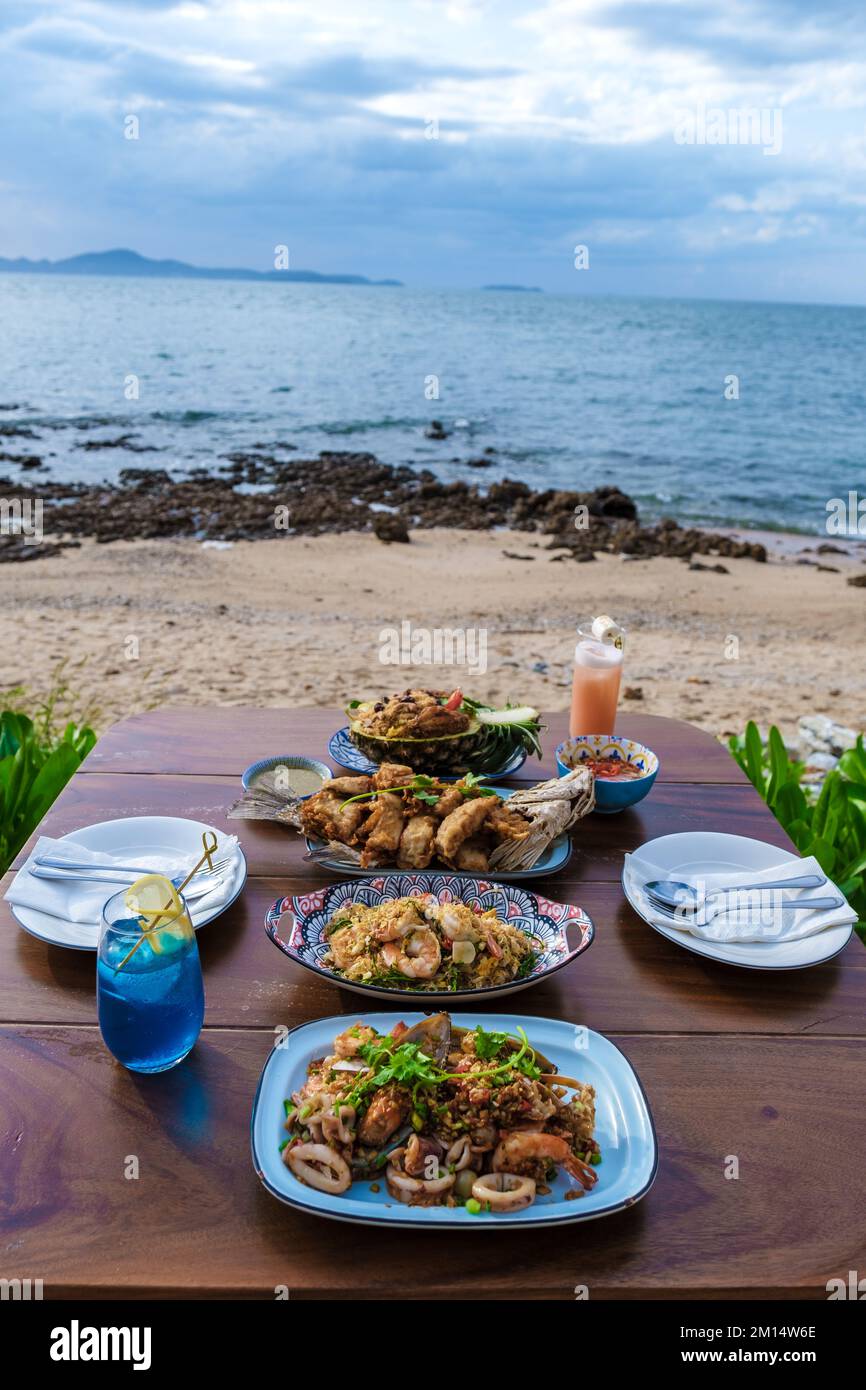 Dinner table with Thai food and bbq fish on the beach of Pattaya ...