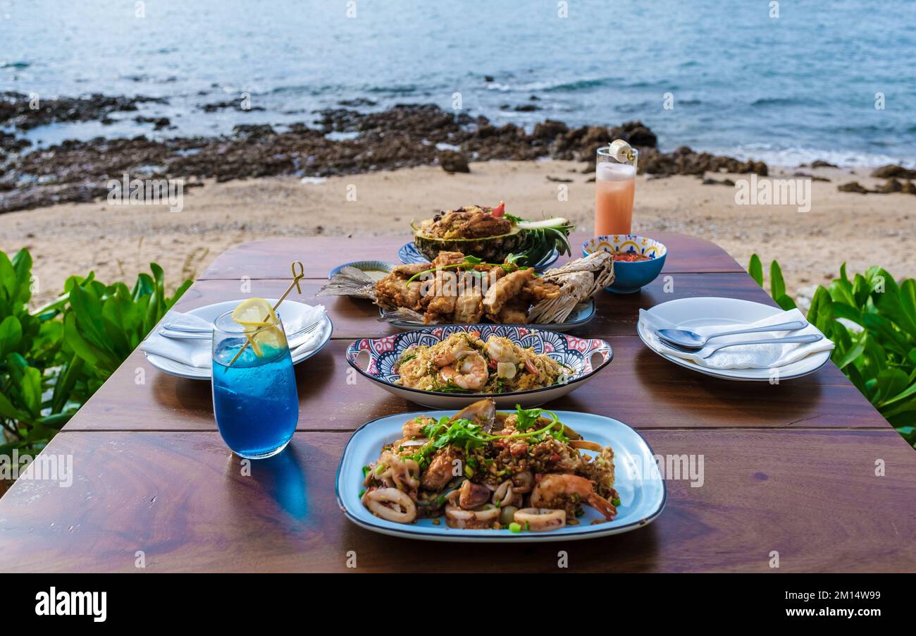 Dinner table with Thai food and bbq fish on the beach of Pattaya ...