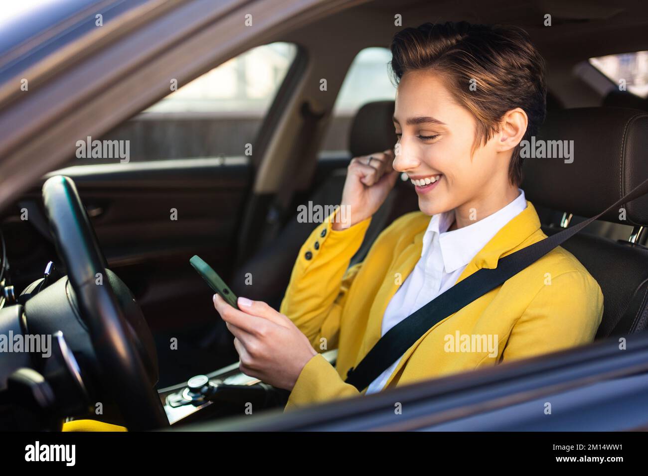 Beautiful young woman with short hair driving car in the city - Pretty ...