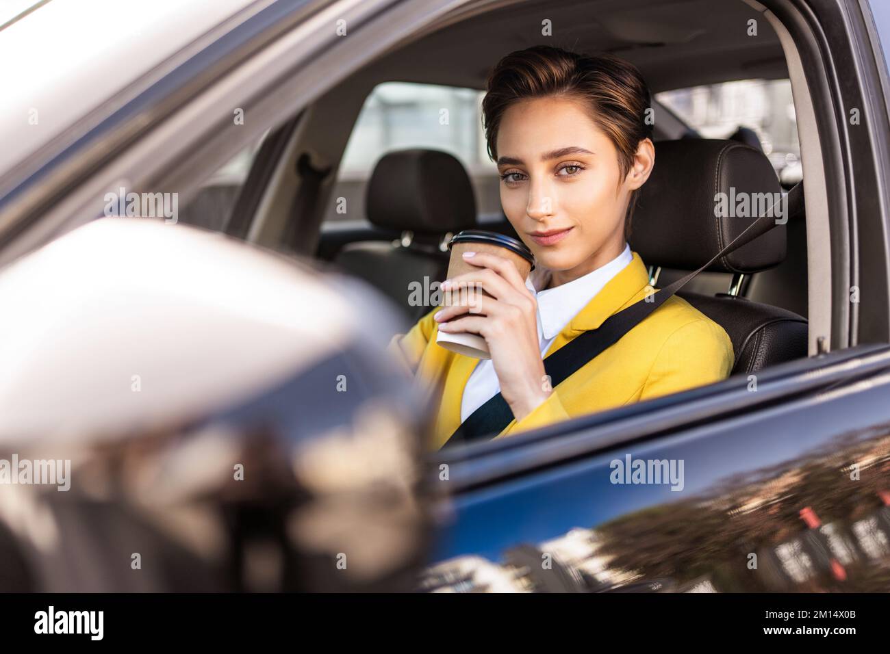 Beautiful young woman with short hair driving car in the city - Pretty ...