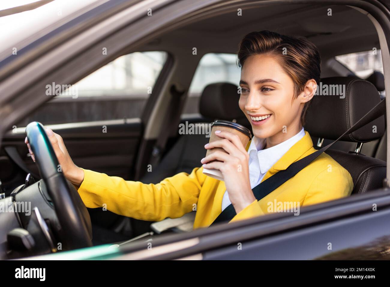Beautiful young woman with short hair driving car in the city - Pretty ...