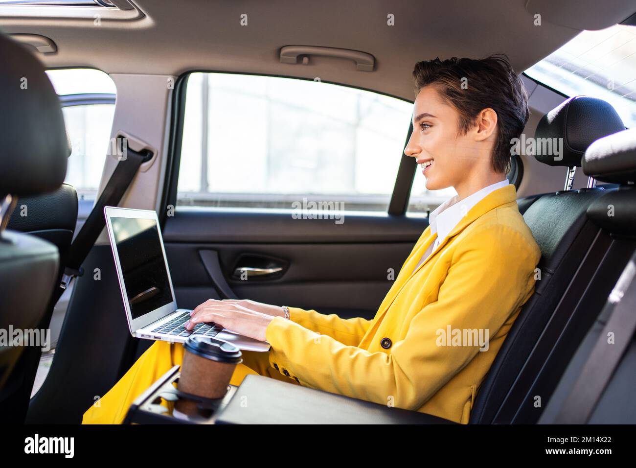 Beautiful young woman with short hair driving car in the city - Pretty ...