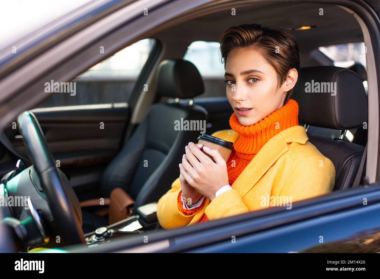 Beautiful young woman with short hair driving car in the city - Pretty ...