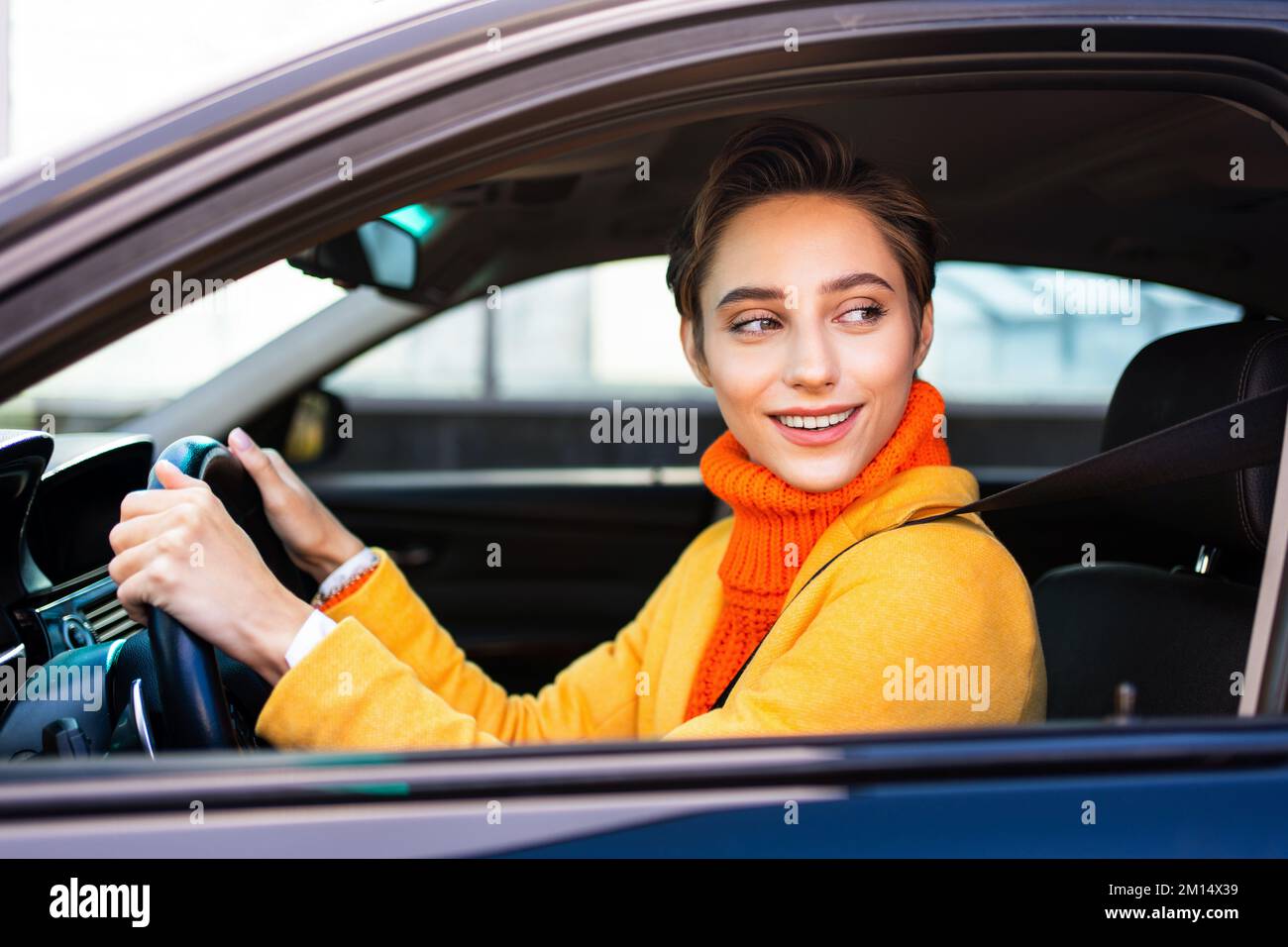 Beautiful young woman with short hair driving car in the city - Pretty ...