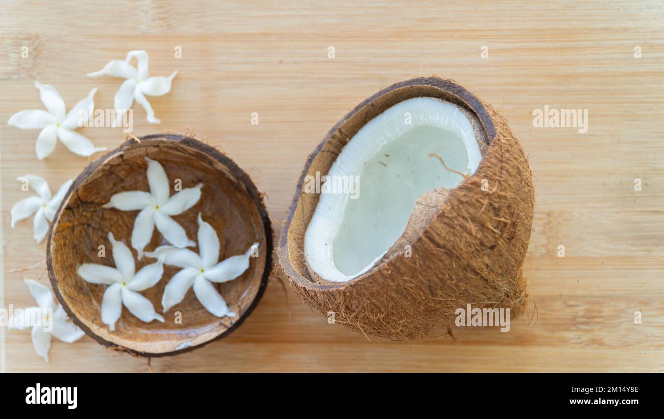 Open coconut nut on a wooden background with white flowers Stock Photo ...