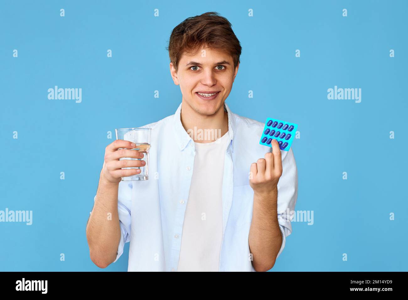 man holding pill and glass of water on blue background Stock Photo - Alamy