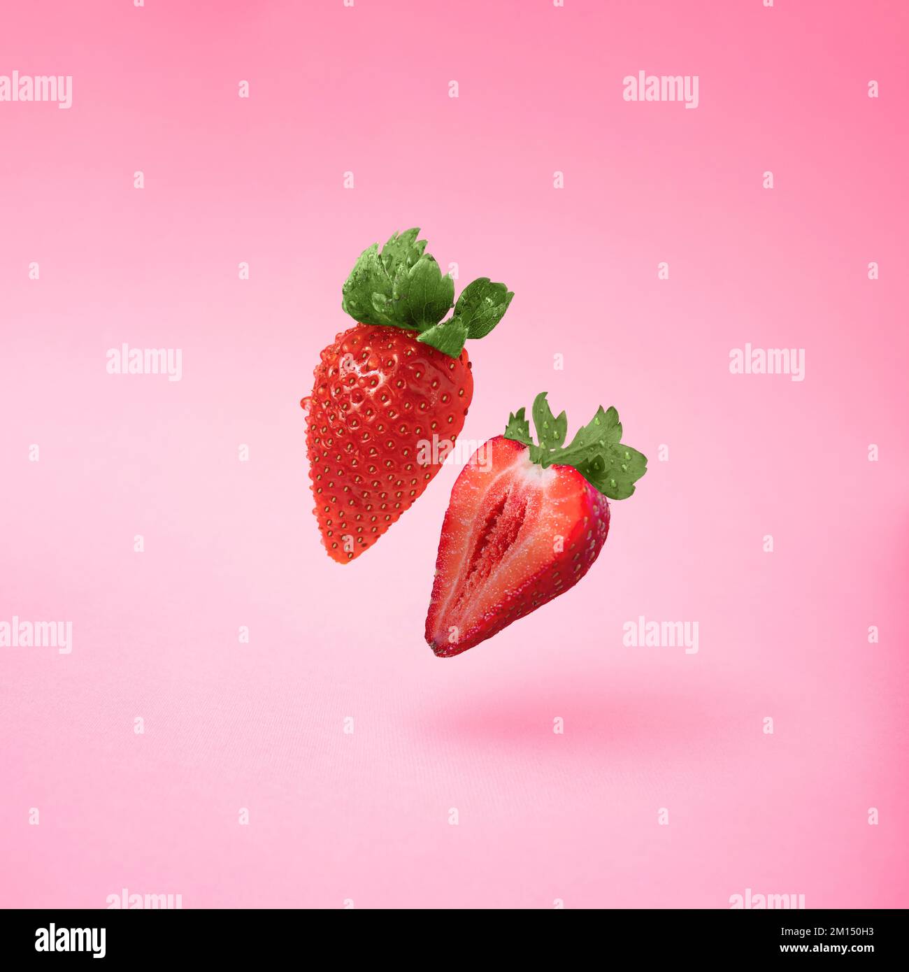 A 3D render of fresh cut strawberry floating in the air on the pink ...