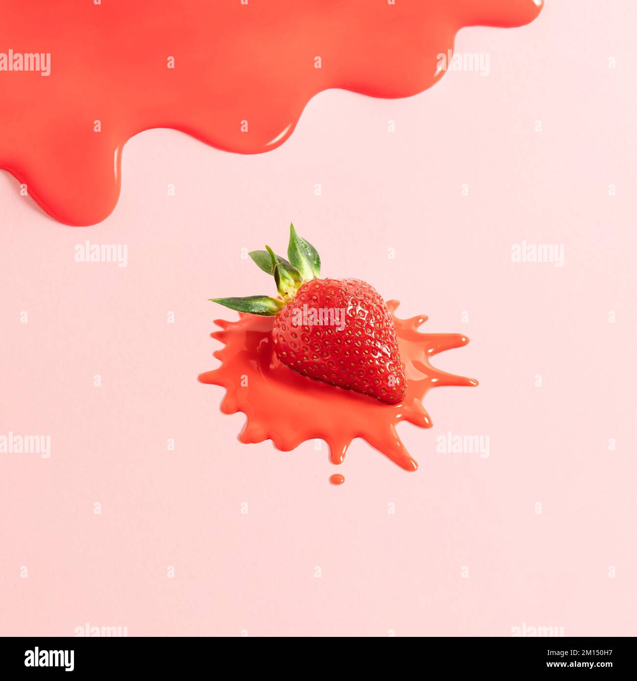 A fresh cut strawberry in a red melting cream on pink background Stock ...