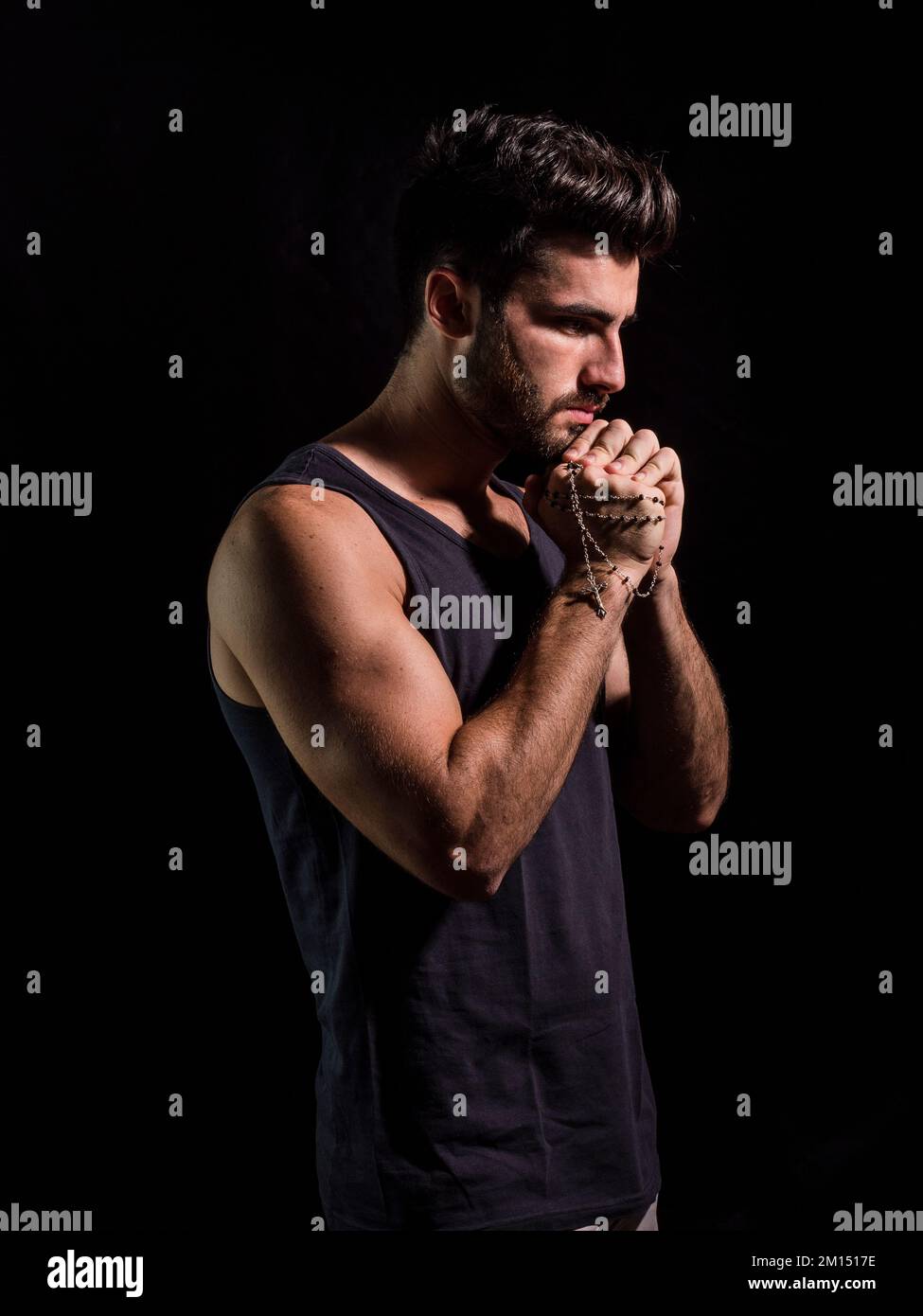 Spiritual man praying with rosary in dark Stock Photo - Alamy