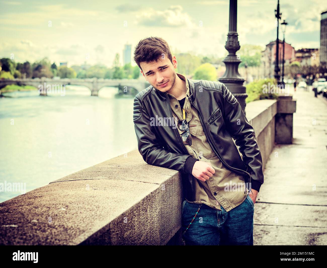 Three-quarter length of young man standing beside picturesque river in ...