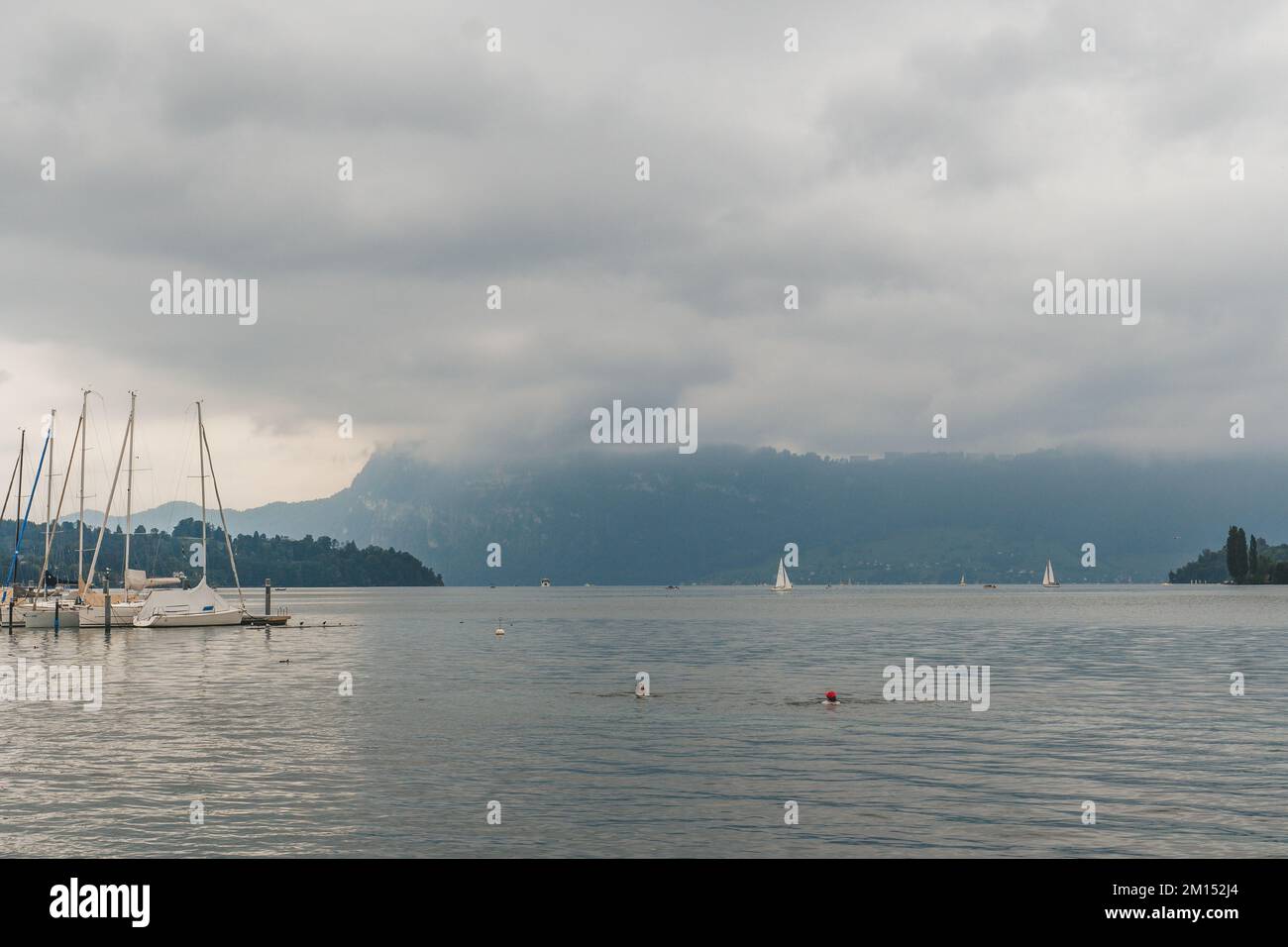 People swimming near a docking with boats in the tranquil Lake Lucern ...