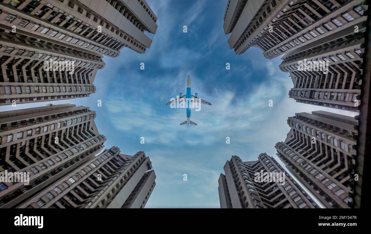 A low angle shot of an Airplane flying over skyscrapers under a blue ...