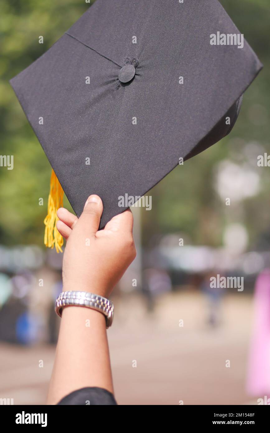 Student hold hats in hand during commencement success on yellow ...