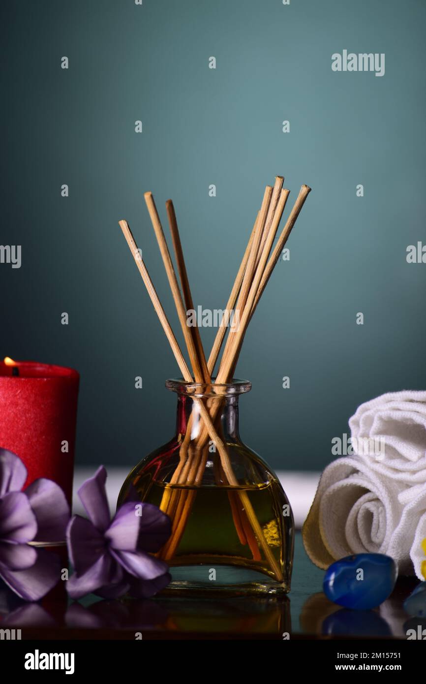 Vertical image of reed diffuser with flowers and candles on table still ...