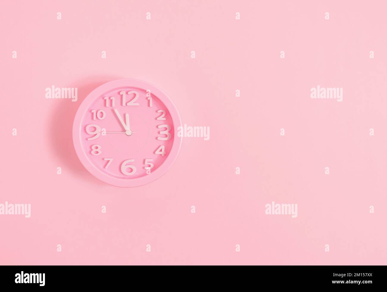 A pastel pink wall alarm clock on pink painted wall-Christmas Eve or ...