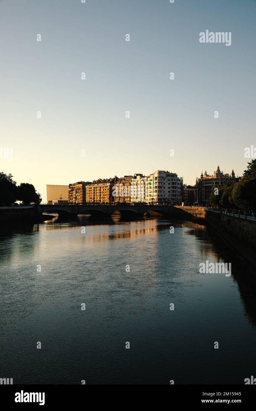 A vertical of lake reflecting buildings at sunrise, clear, purple sky ...