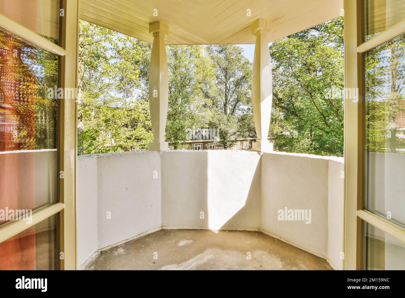 an empty balcony with trees in the background and sun shining through ...