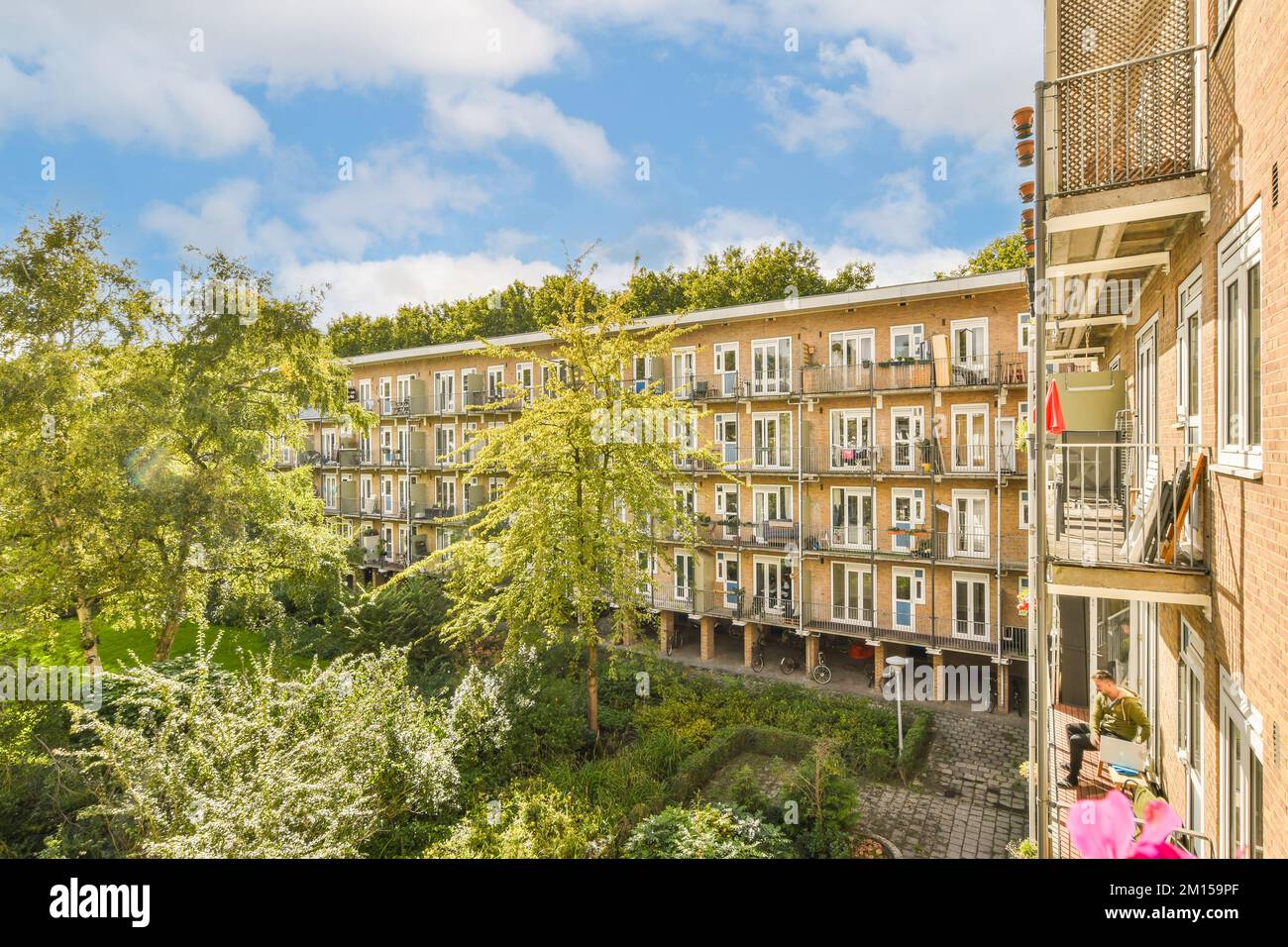 an apartment complex with trees and people on the balcony looking out ...