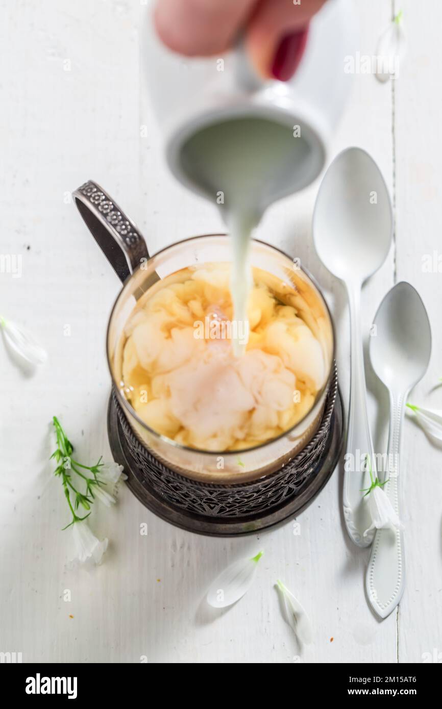 Pouring milk into tea with filigree holder. Traditionally brewed tea ...