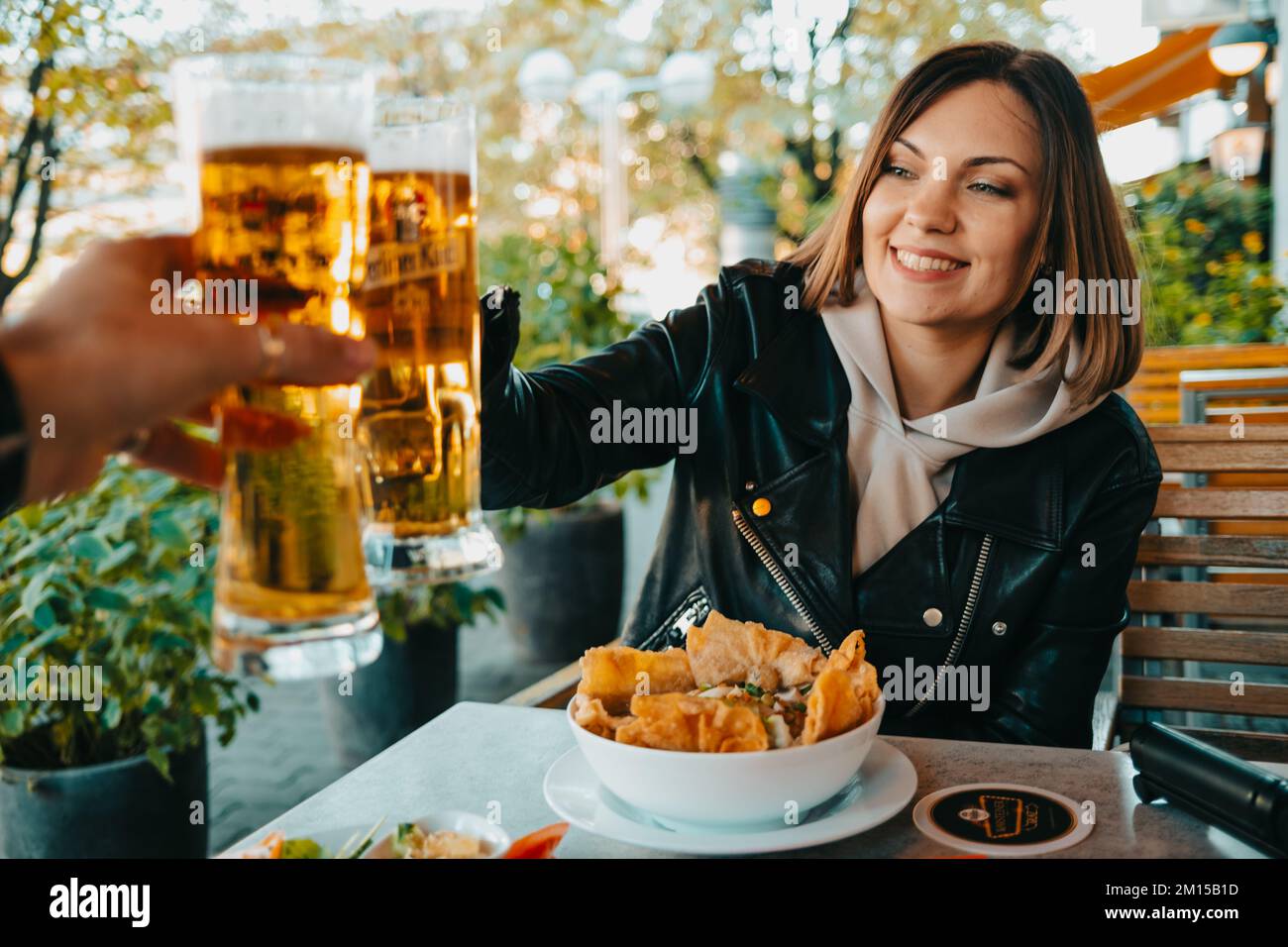 Happy woman clink beer glasses with man in asian cafe in Germany ...