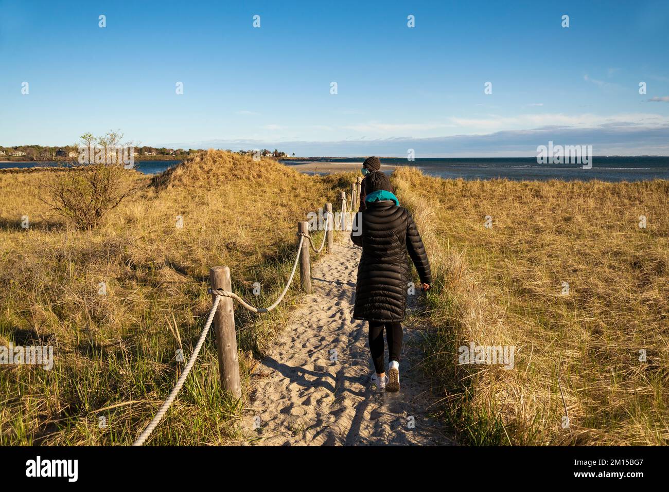 Two women walking on a dirt path at a beach in Maine in the wintertime ...