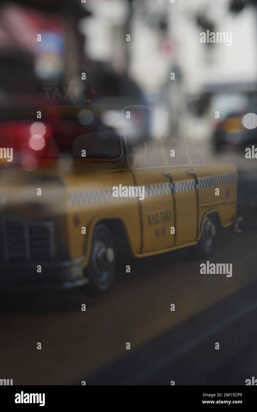 taxi toy car on windowsill and the street of tel aviv is reflected from ...