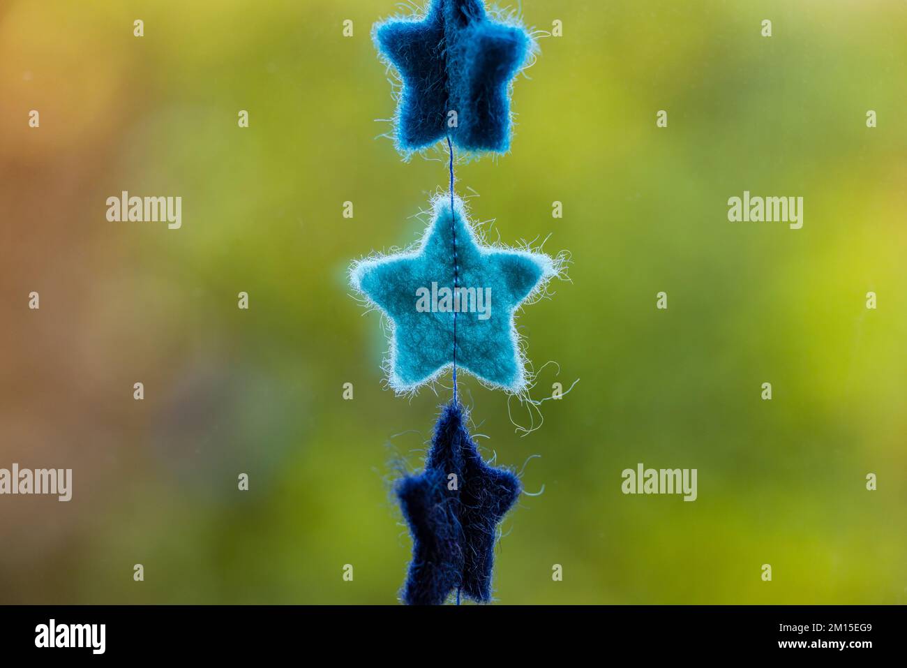 Close-up of felt star on thread of garland cropped against natural ...