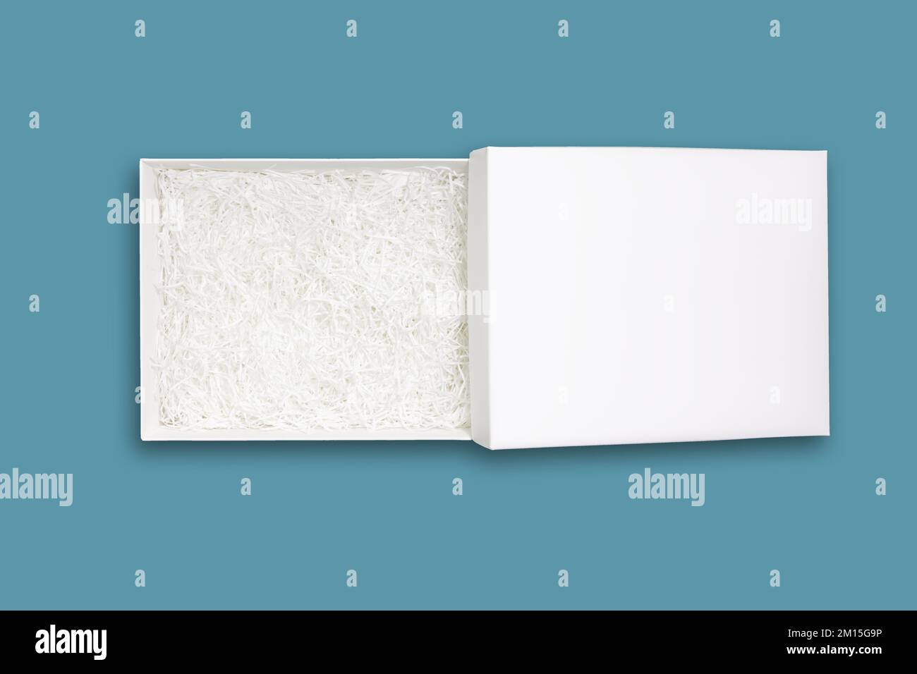 Opened gift box with shredded paper on blue background. White paper box ...