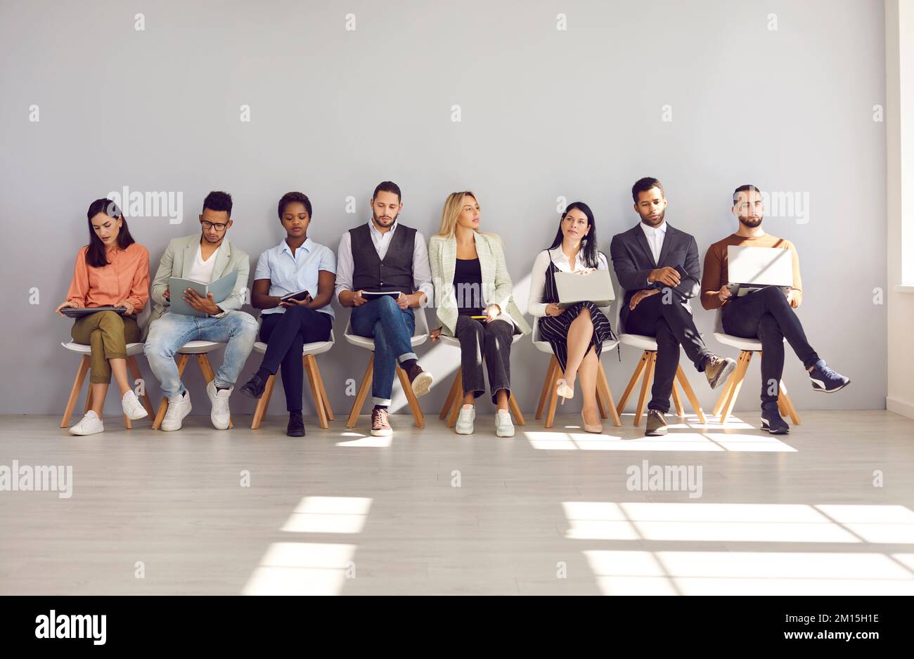 Group of different multiethnic people sitting in row in waiting room ...