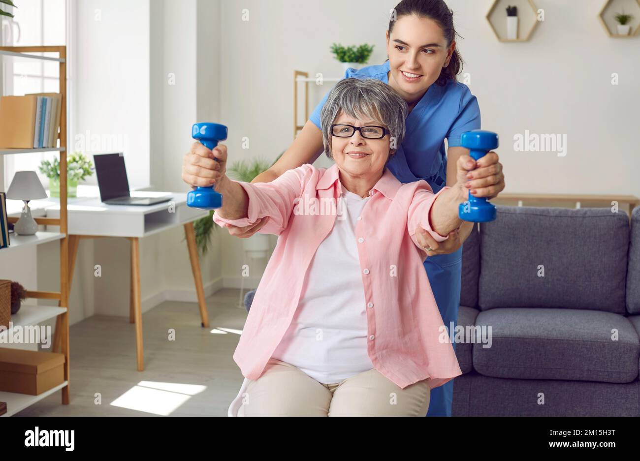 Nurse helping a happy senior woman do rehabilitation fitness exercises ...