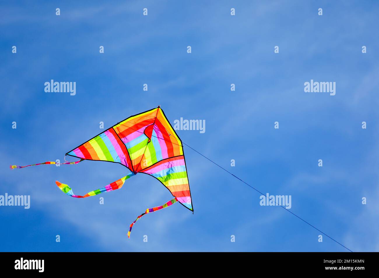 big rainbow colored kite flying high in the blue sky with some white ...